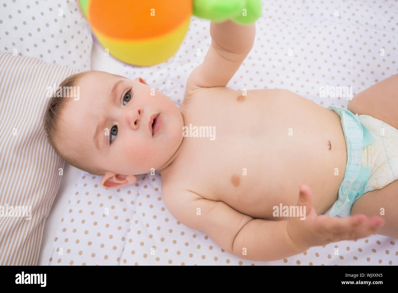 Baby lying on back holding toy hi-res stock photography and images - Alamy
