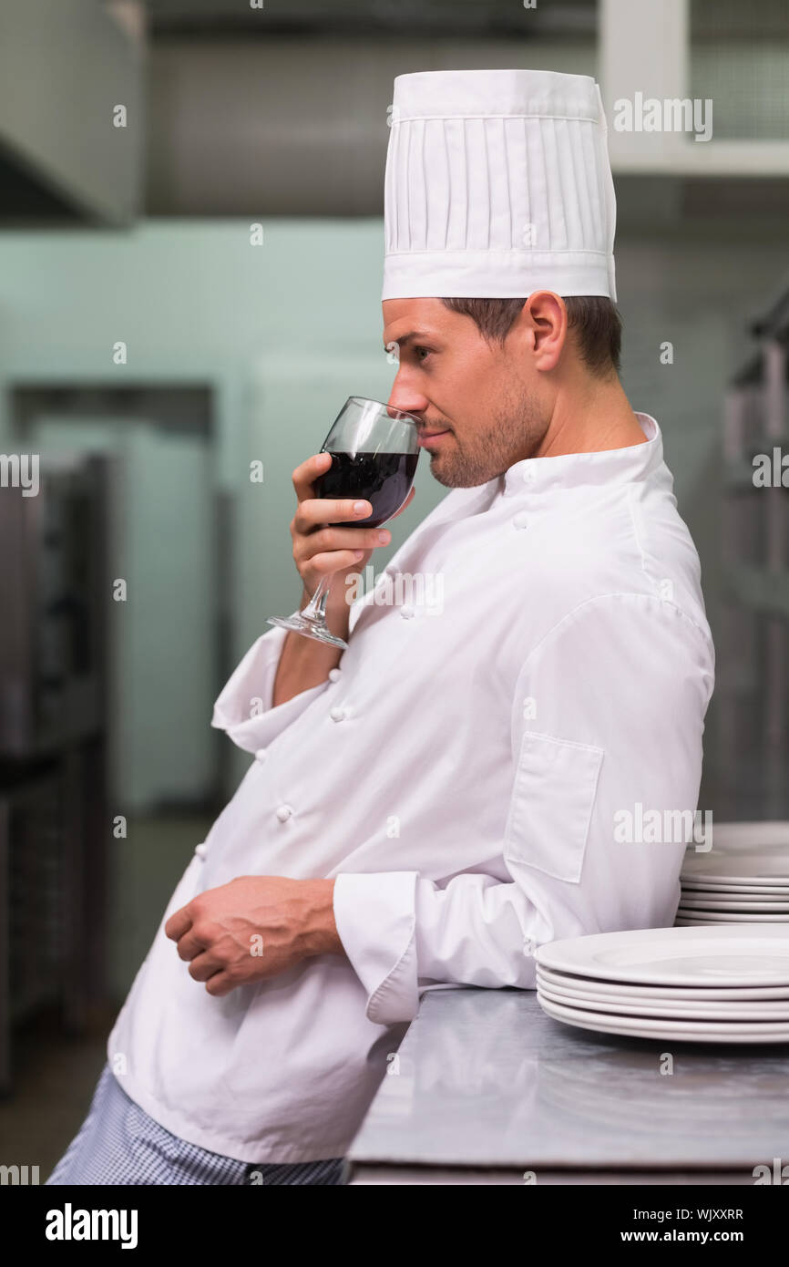 Chef relaxing with glass of red wine after work in a commercial kitchen ...