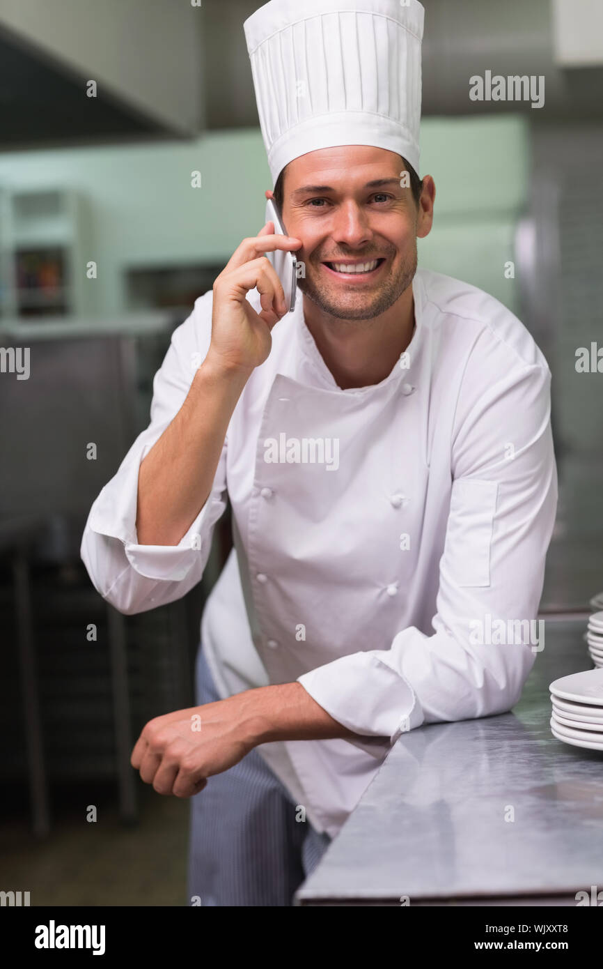 Smiling chef talking on the phone in a commercial kitchen Stock Photo ...