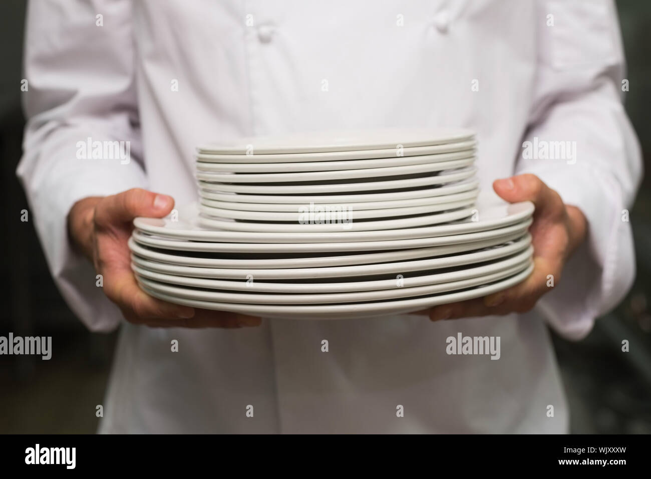Chef holding stack of plates in a commercial kitchen Stock Photo - Alamy