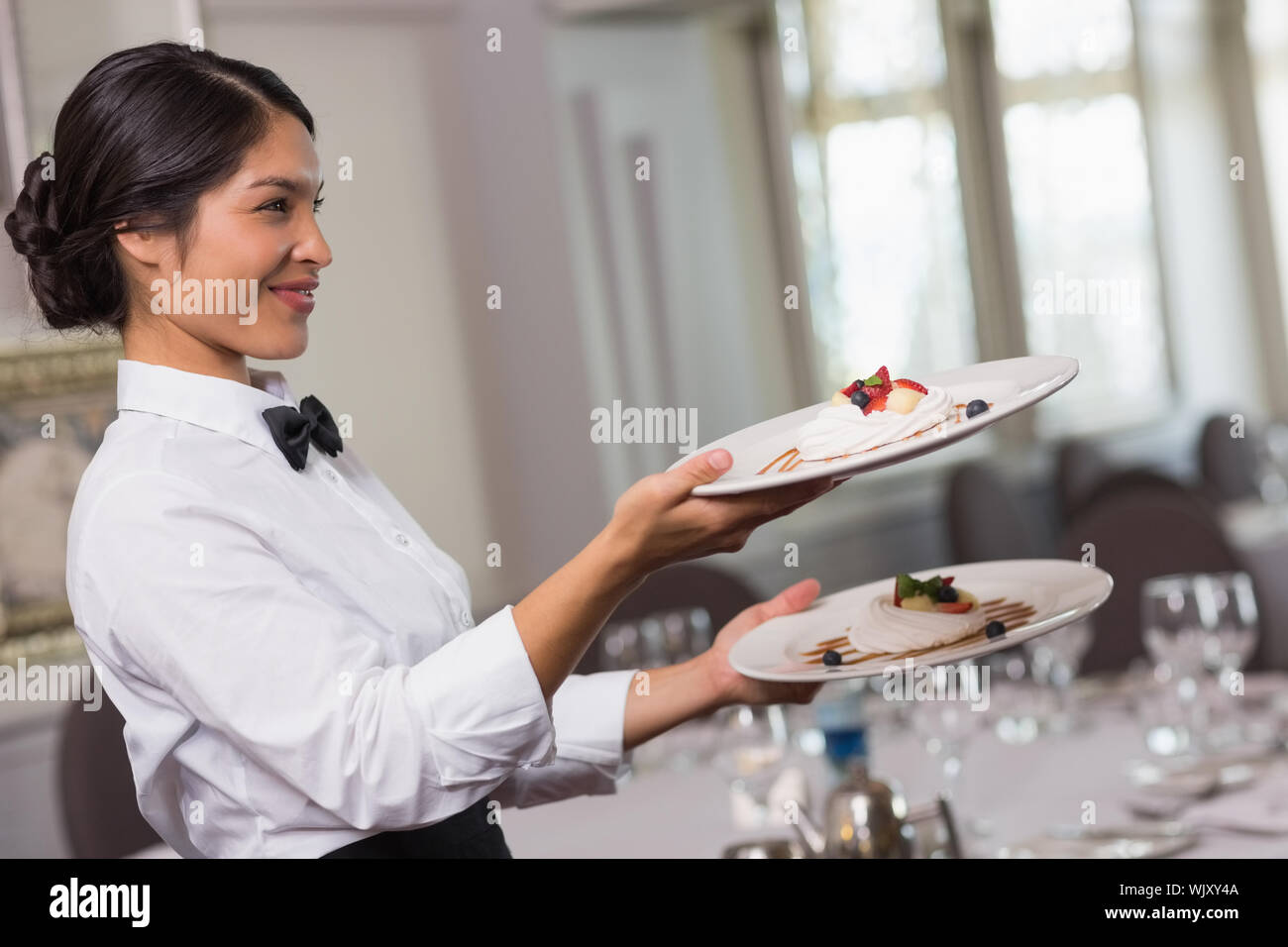 Pretty waitress holding two dessert plates in a fancy restaurant Stock ...