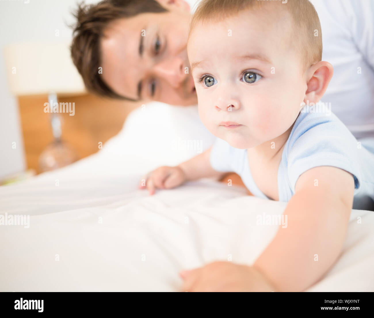 Father playing with baby son in blue babygro at home in bedroom Stock ...