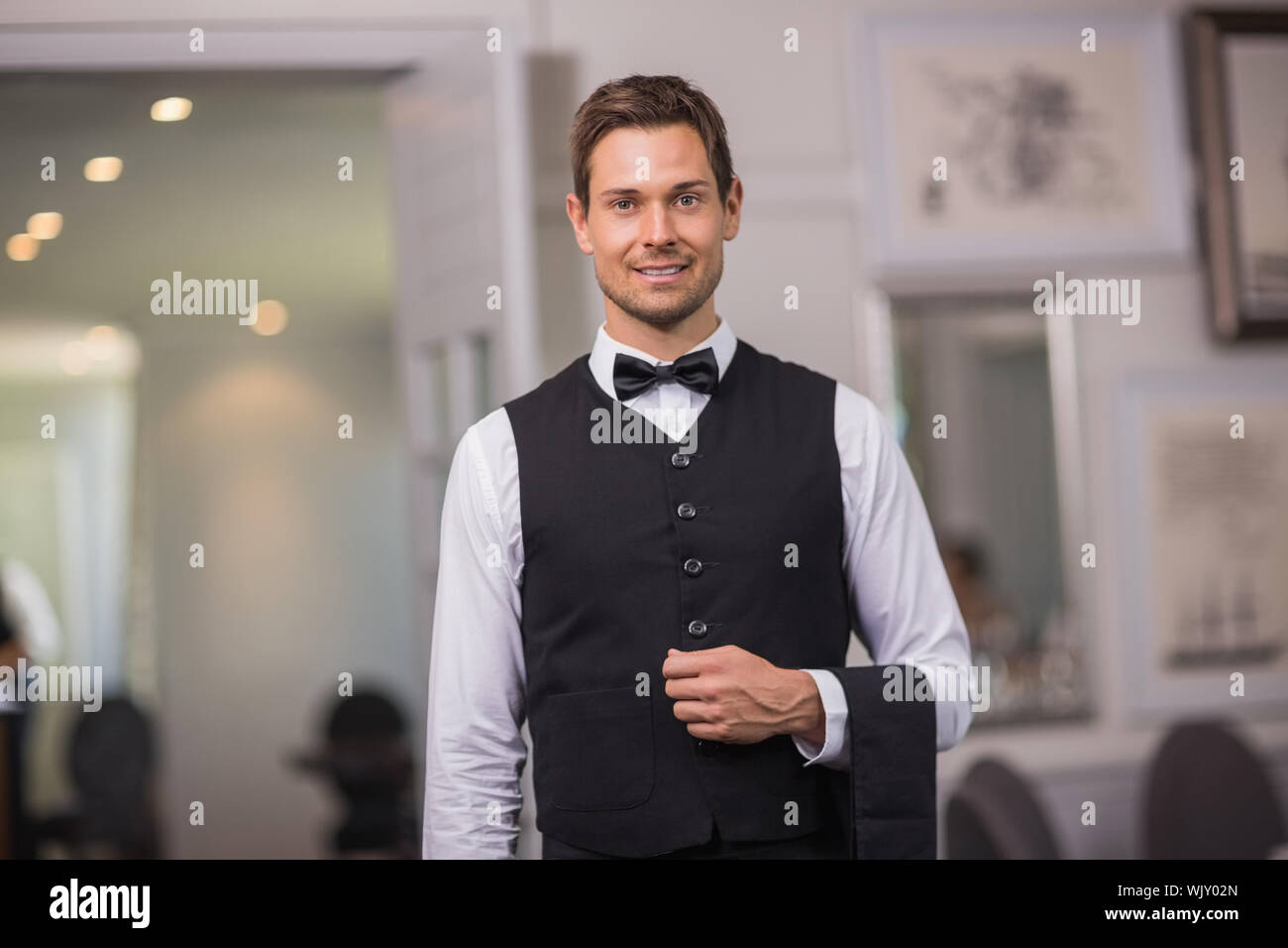 Handsome waiter smiling at camera in a fancy restaurant Stock Photo - Alamy