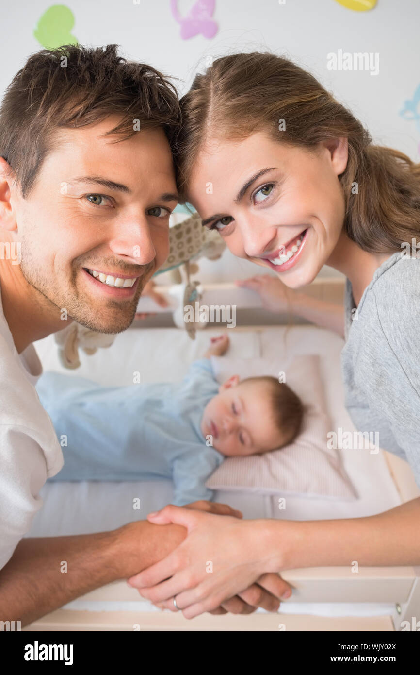 Happy parents watching over baby son in crib at home in bedroom Stock ...