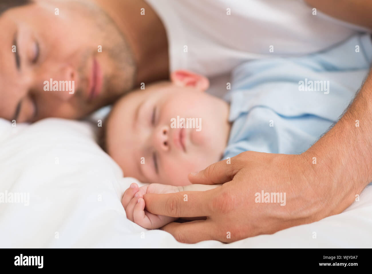 Happy father lying with baby son sleeping at home in bedroom Stock ...