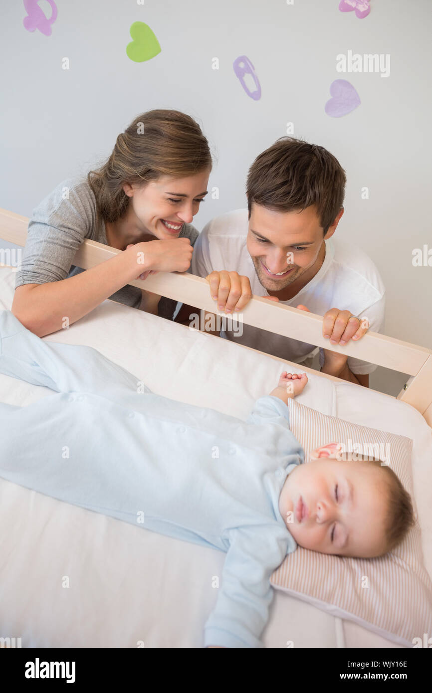 Happy parents watching over baby son in crib at home in bedroom Stock ...