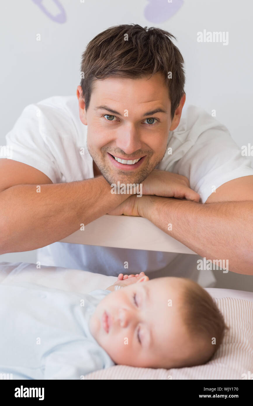 Happy father watching over baby son in crib at home in bedroom Stock ...