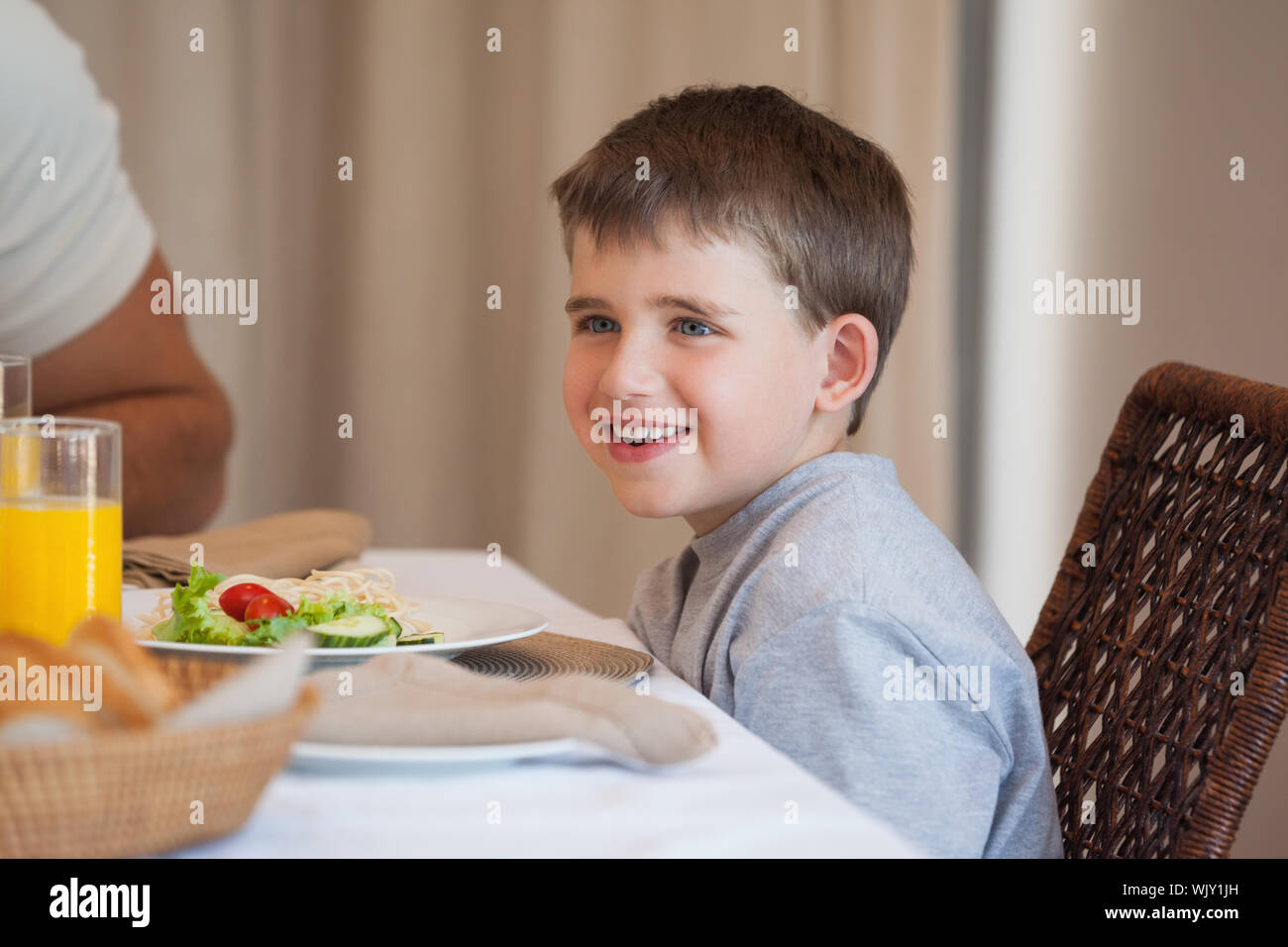 Smiling young boy sitting at dining table in the house Stock Photo - Alamy