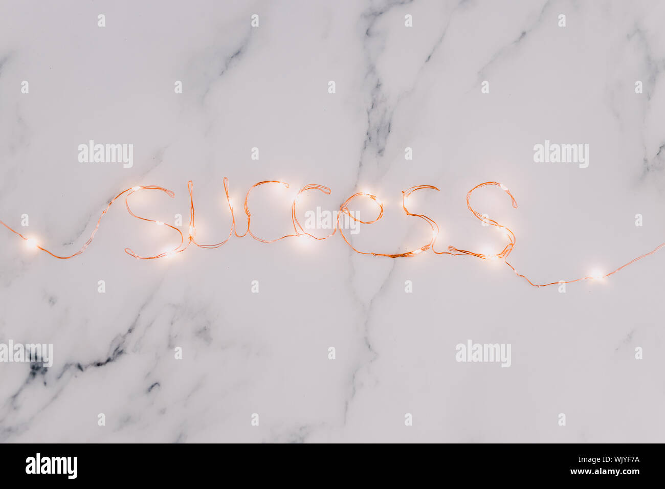 Success message made of fairy lights on marble desk background ...