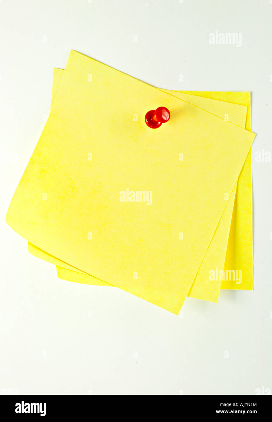 Three yellow sticky paper pinned with a pin at a white background Stock ...