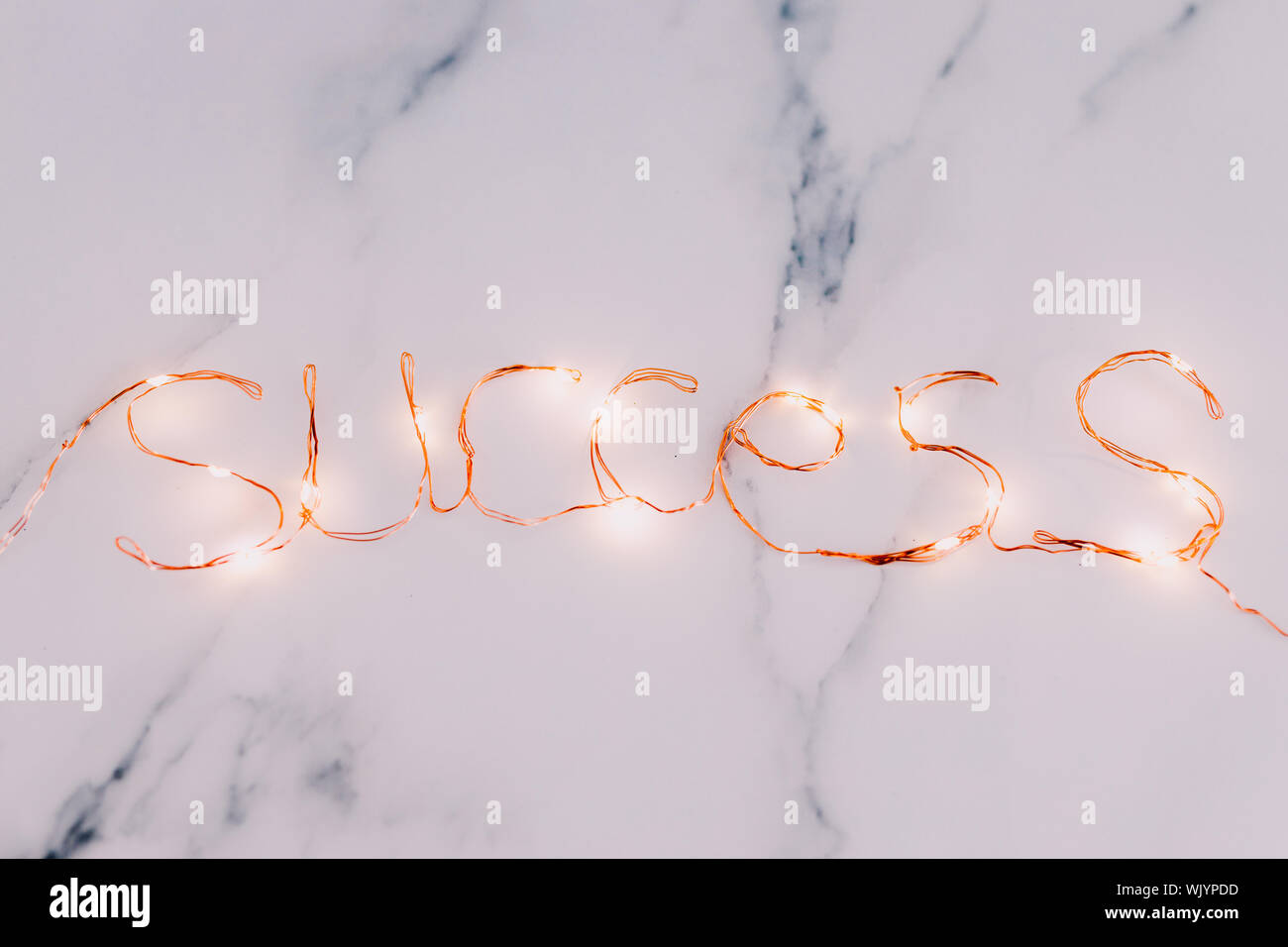Success message made of fairy lights on marble desk background ...