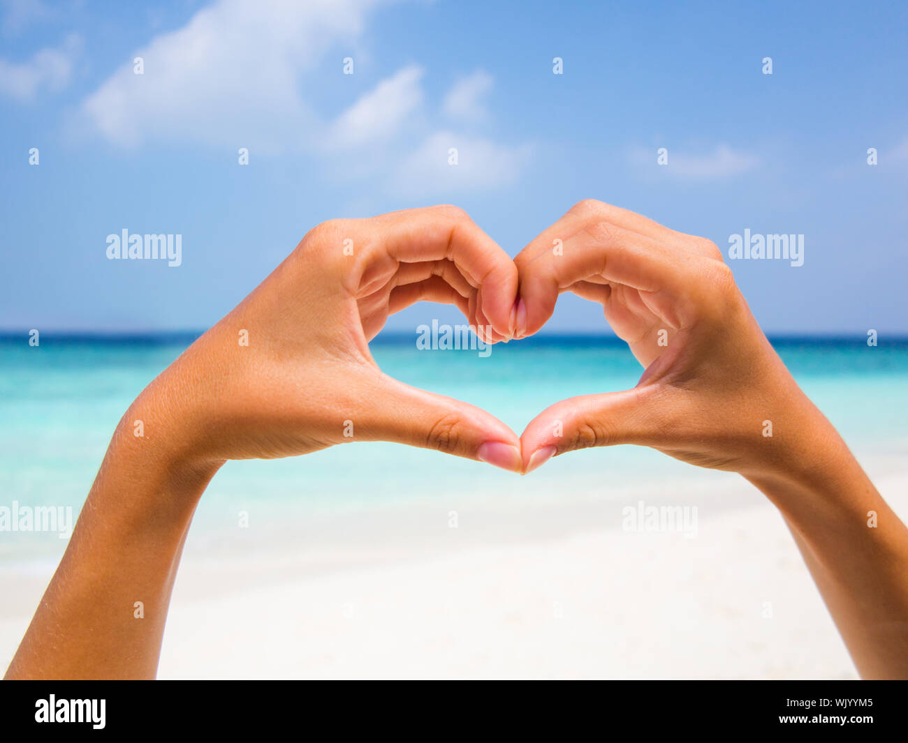 Hands making a heart shape on the beach backgound Stock Photo - Alamy