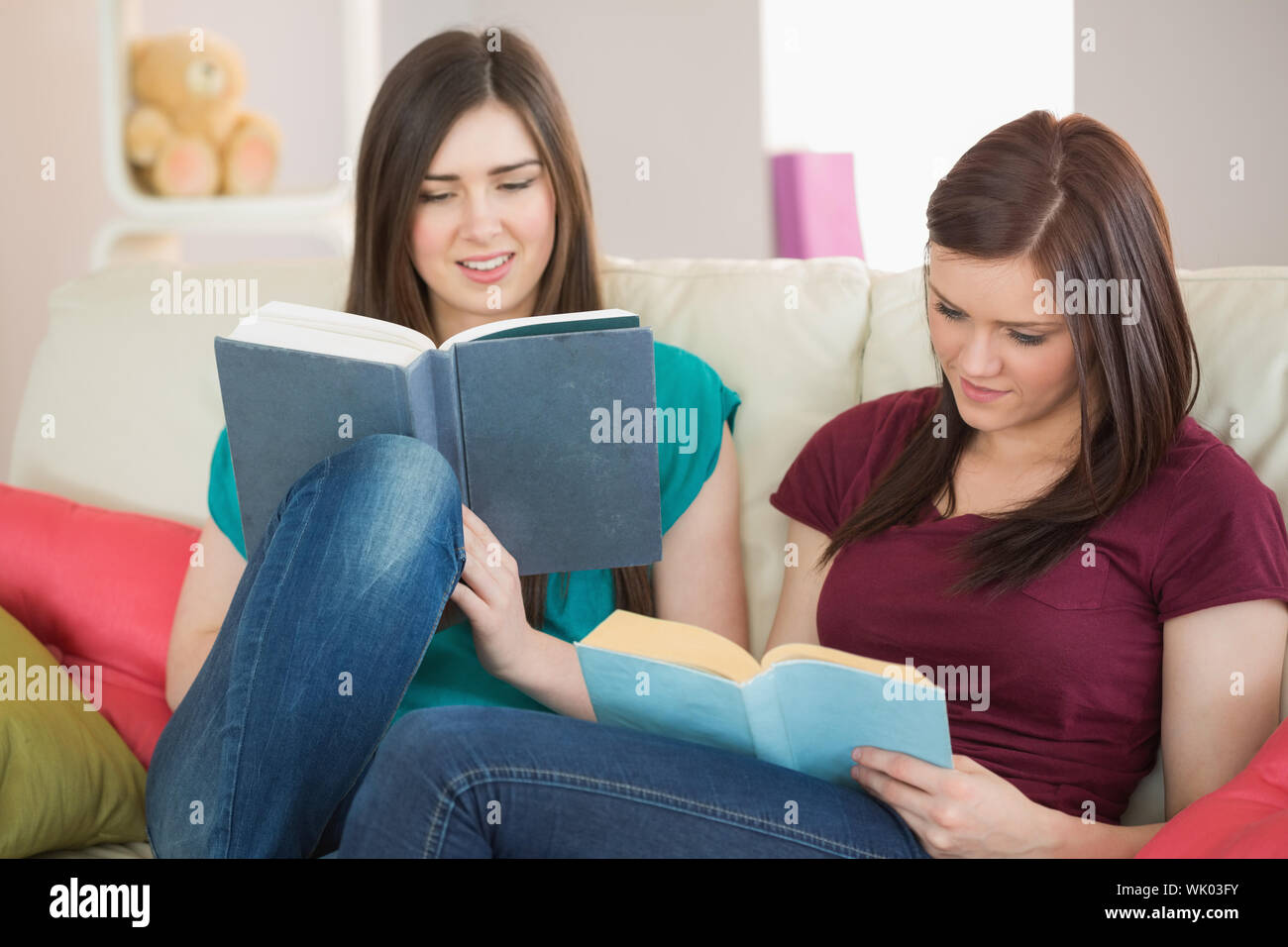 Two girls reading books on the couch Stock Photo - Alamy