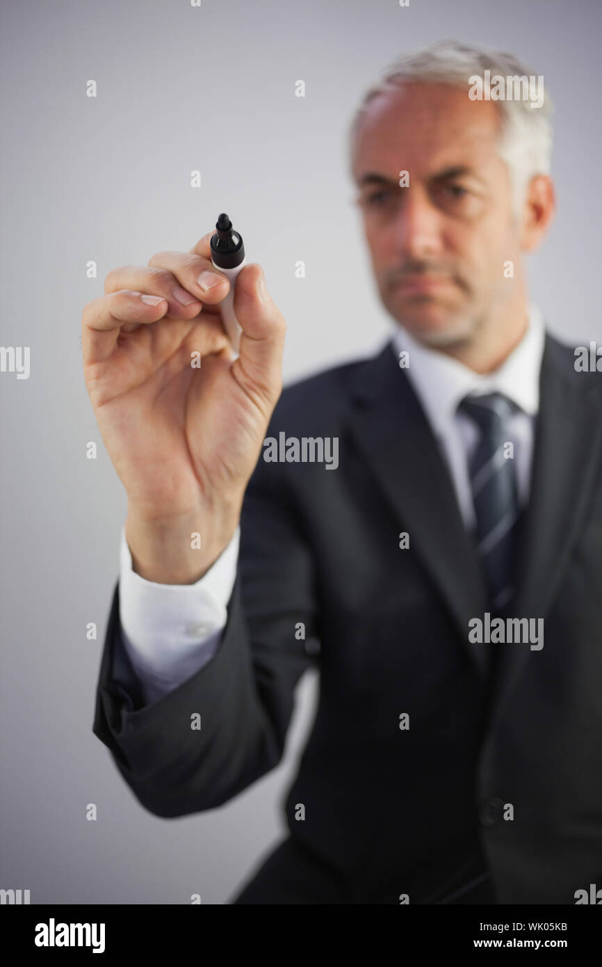 Serious businessman holding a marker and writing Stock Photo - Alamy