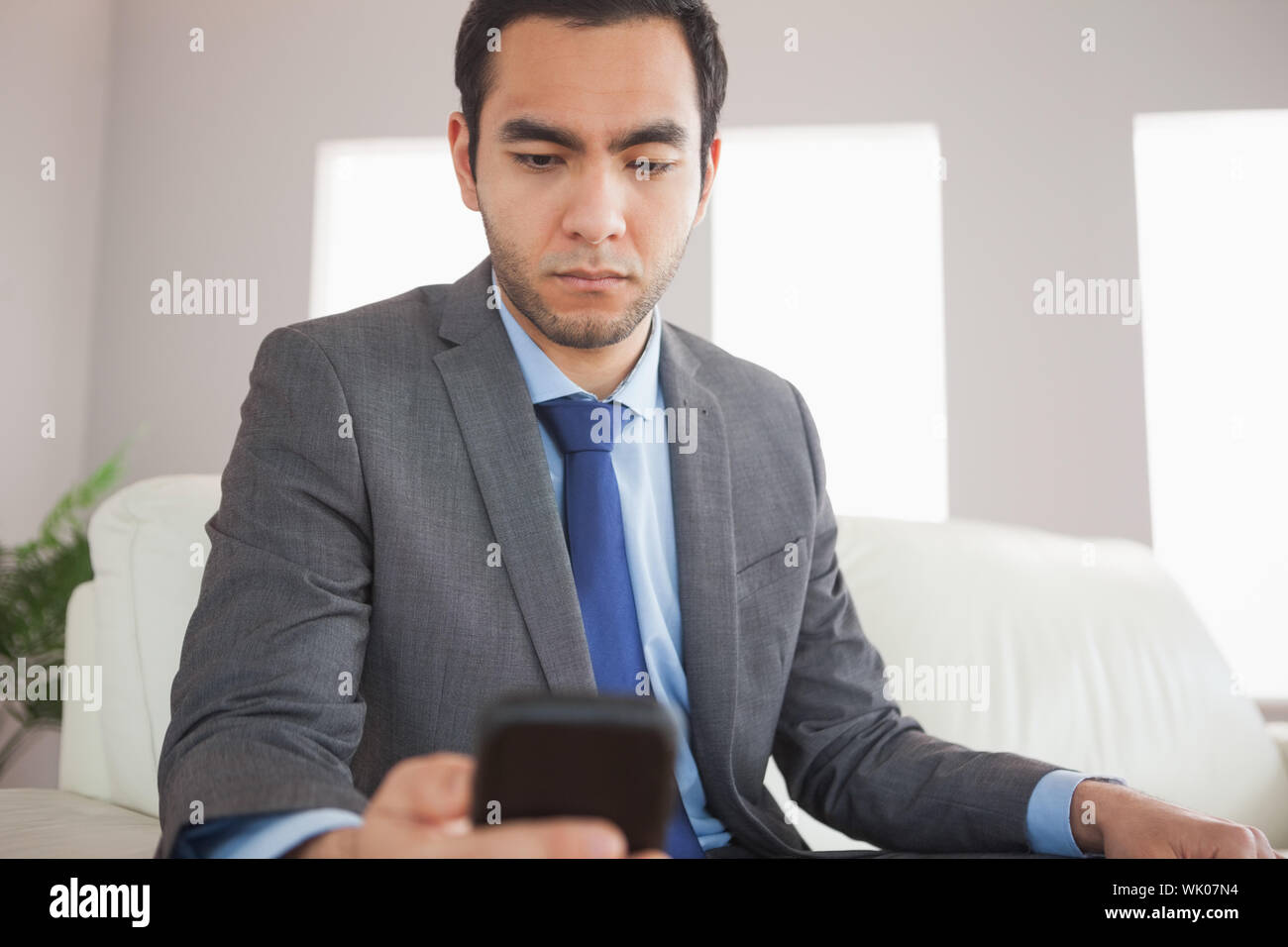 Serious businessman sending a text message Stock Photo - Alamy