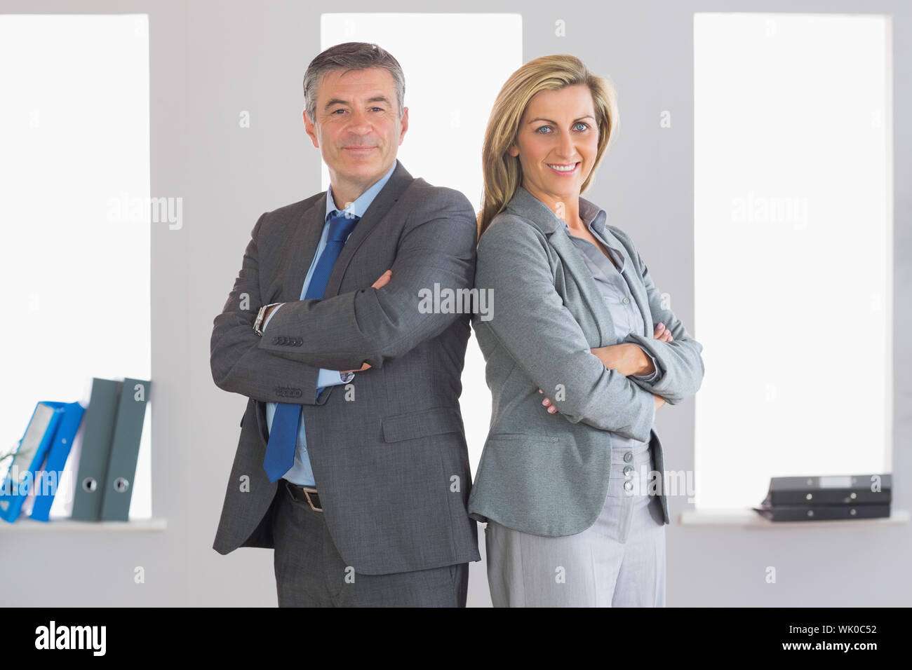Two smiling businesspeople looking standing back-to-back Stock Photo ...