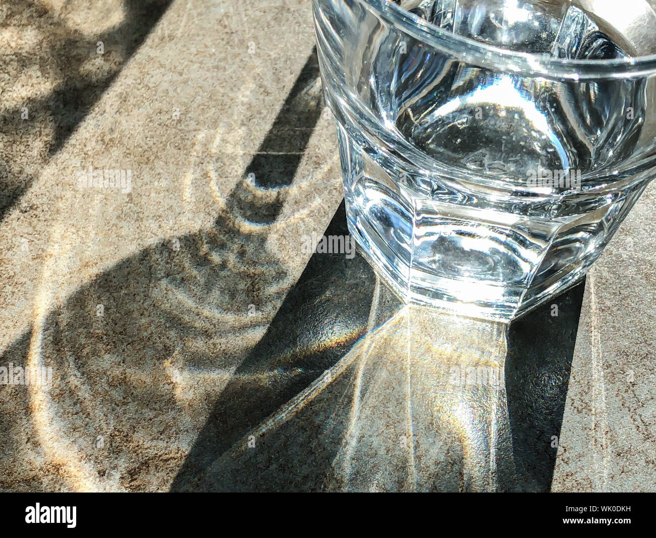 shadow of glass of water reflected sun light against light brown ...