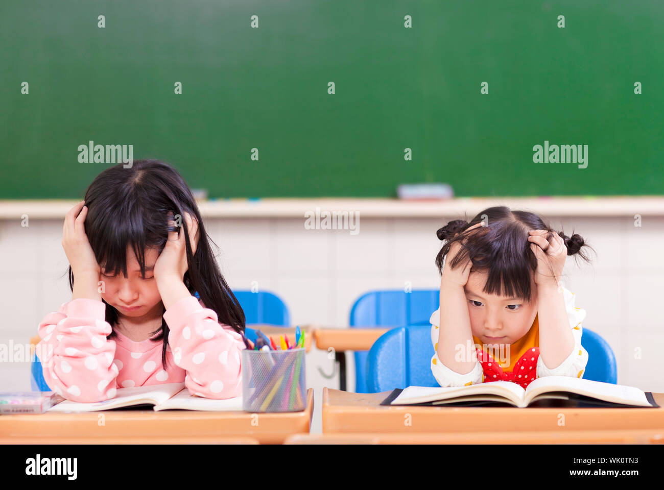 two sad girls doing in homework Stock Photo - Alamy