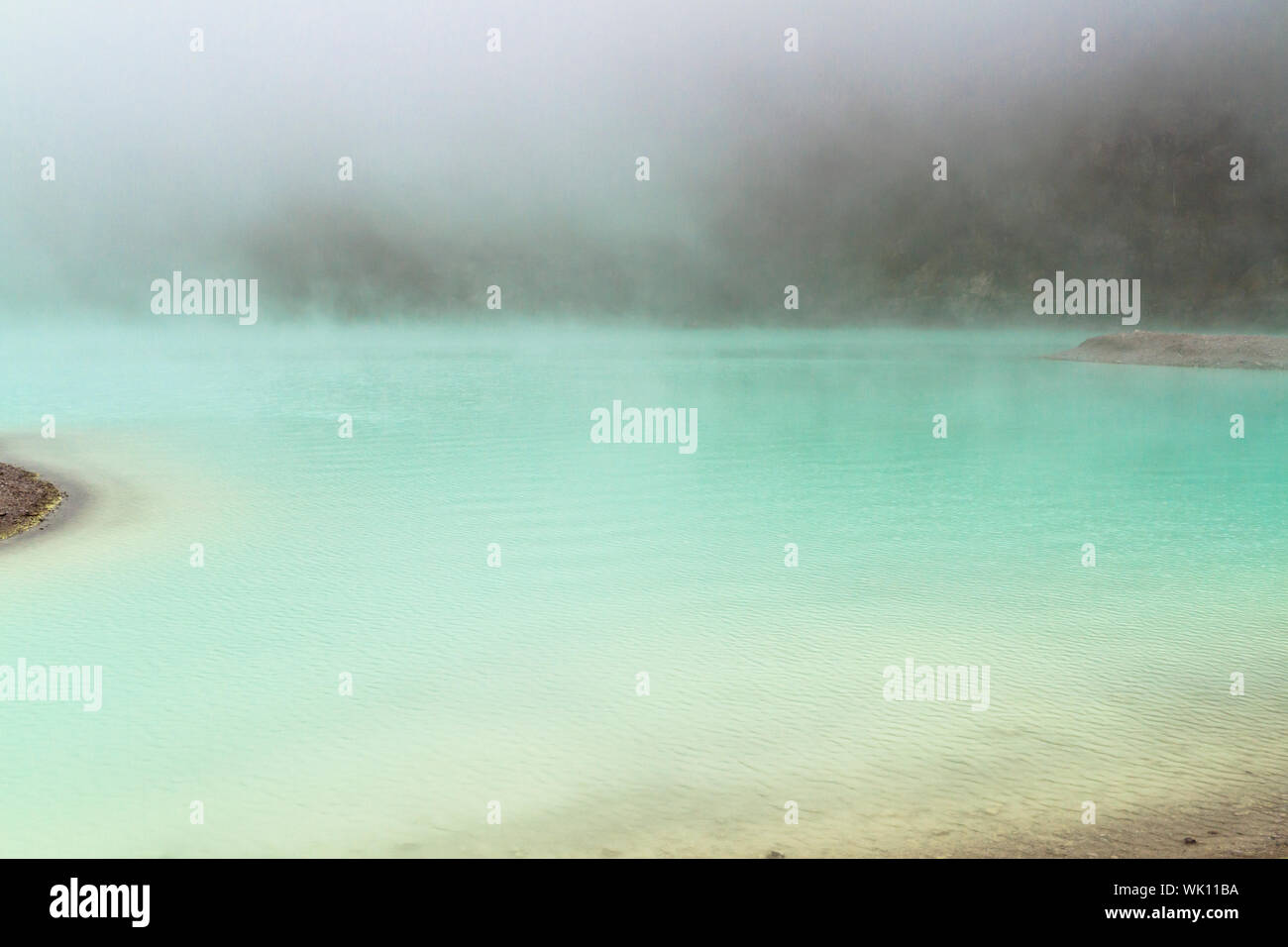 Fog forming over the sand isand in volcanic crater lake surface in ...