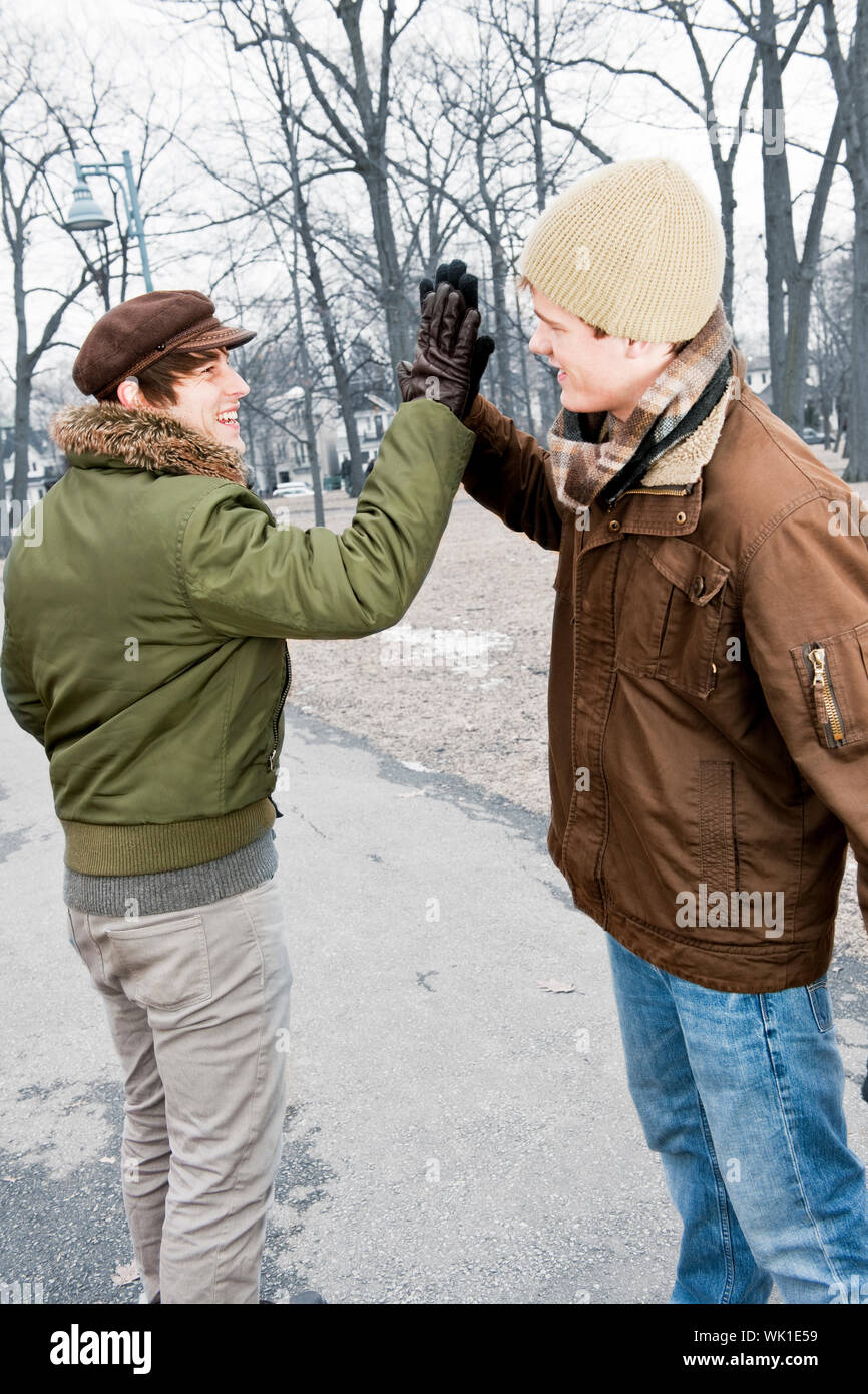 Two young men meeting in winter park giving high five Stock Photo - Alamy