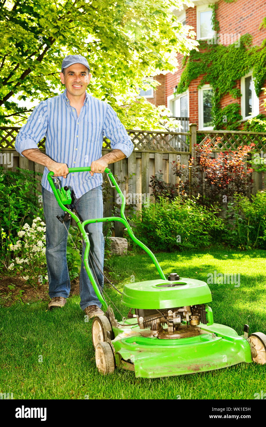 Man with lawn mower in landscaped backyard Stock Photo - Alamy