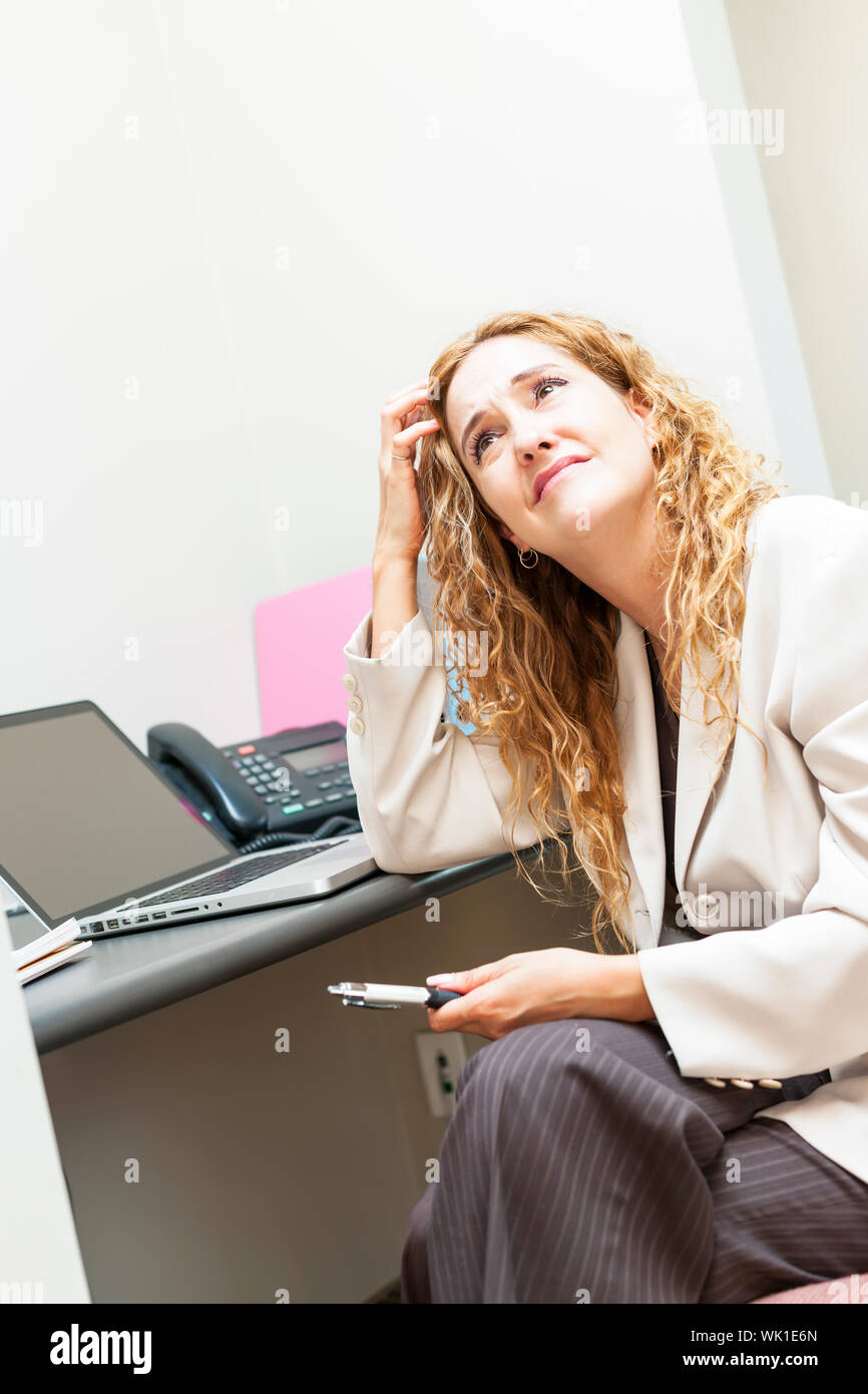 Businesswoman worried in office workstation looking up Stock Photo - Alamy