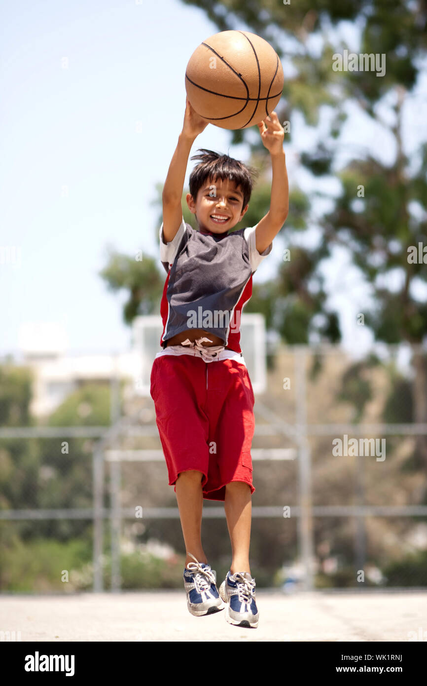 Young basketball player jumping high in air as he throws the ball Stock ...