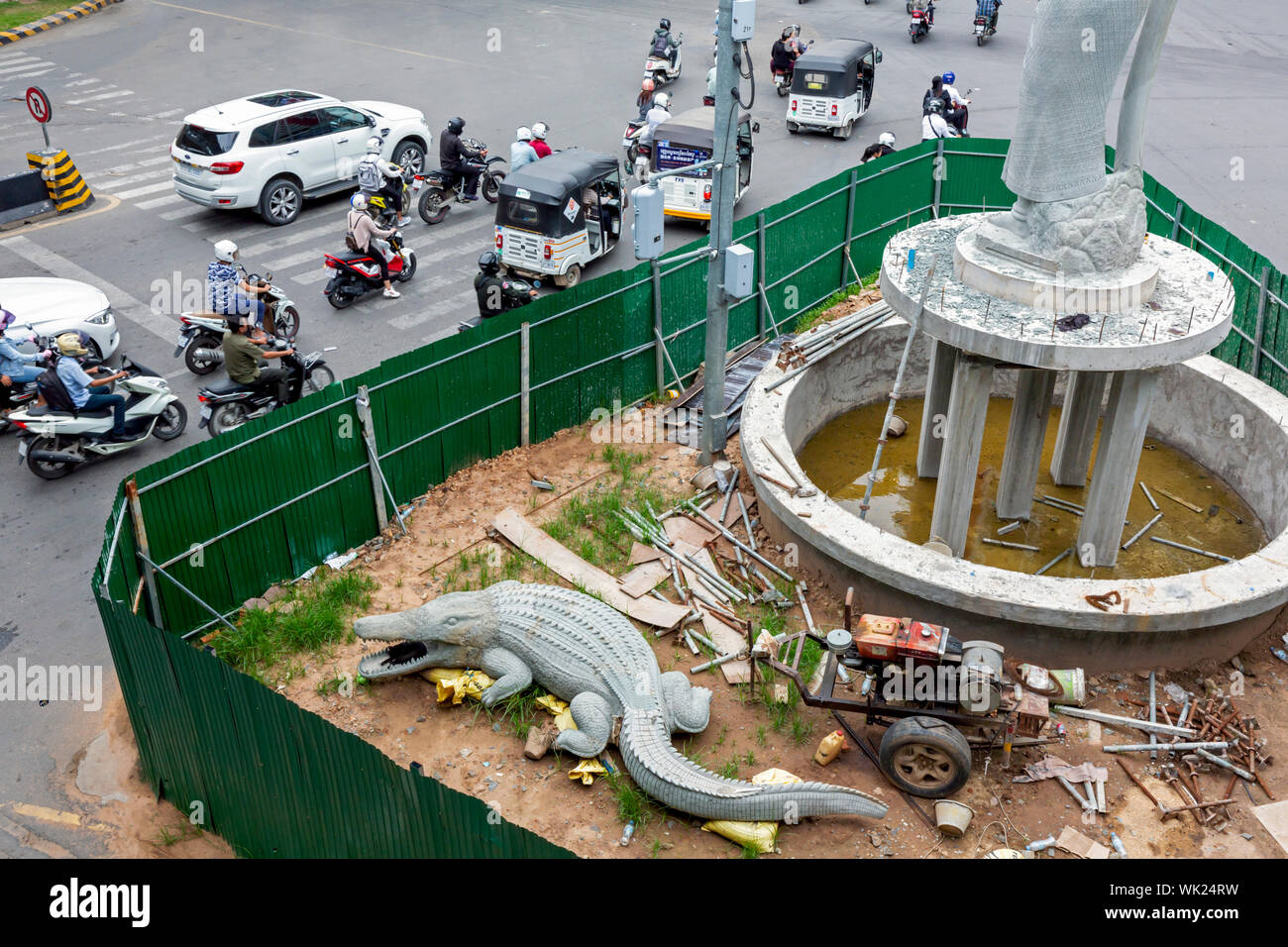 Traffic is flowing on a street in front of a traditional Khmer statue ...