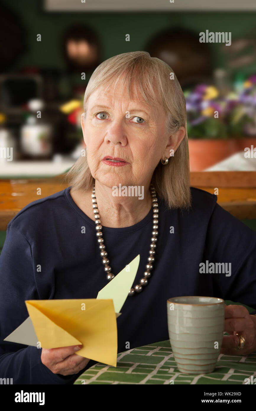 Senior woman at home reading sympathy card Stock Photo - Alamy