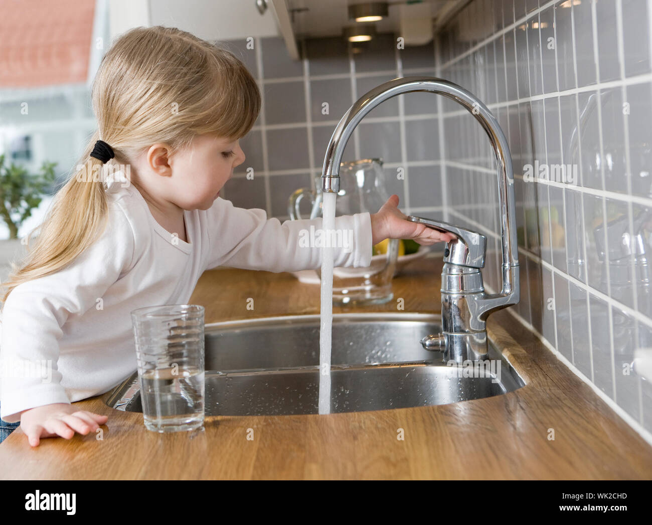 Small Girl in the kitchen drinking water Stock Photo - Alamy