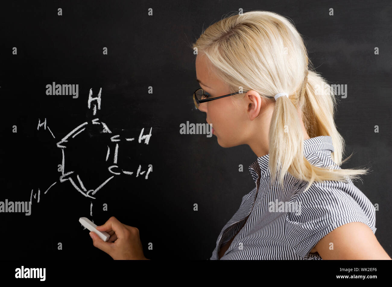 pretty young college student writing on the chalkboard/blackboard ...