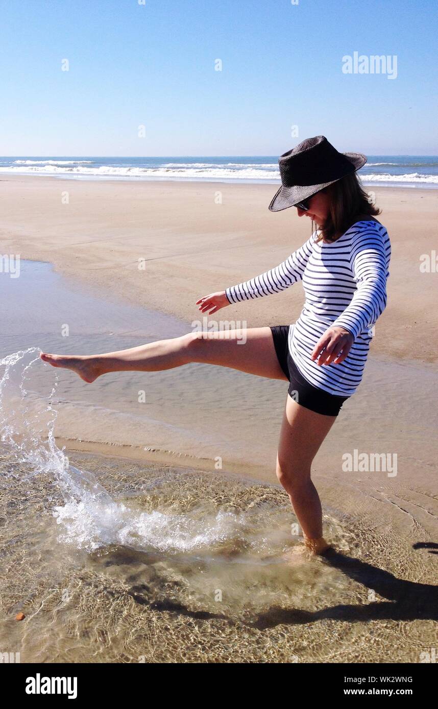 Young woman splashing in water on the beach hi-res stock photography ...