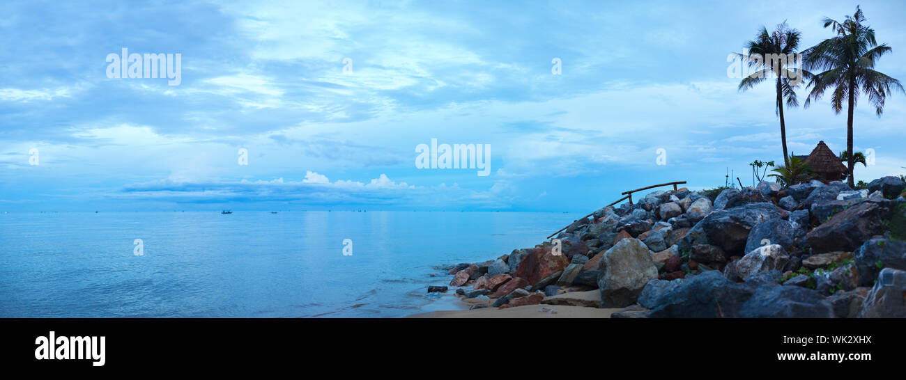 Rainy season. Beautiful exotic bamboo hut and palm trees on the beach ...