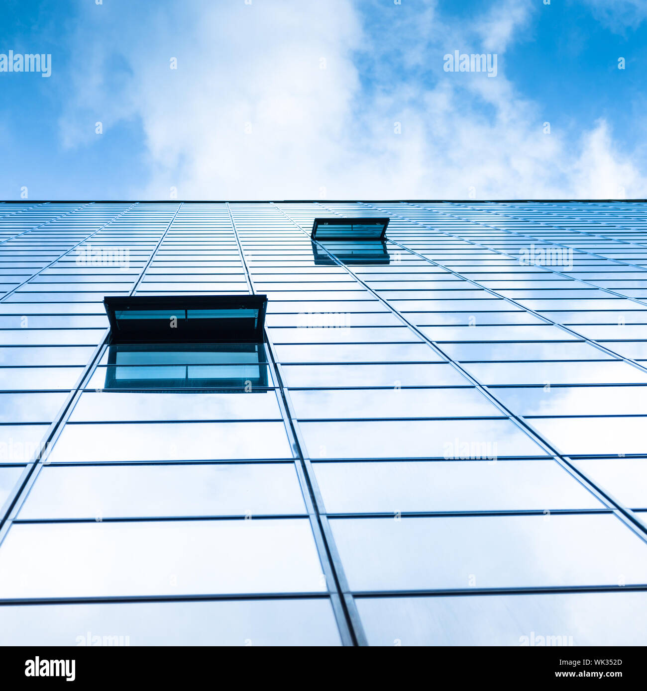 Modern facade of glass and steel with open window reflecting sky and ...