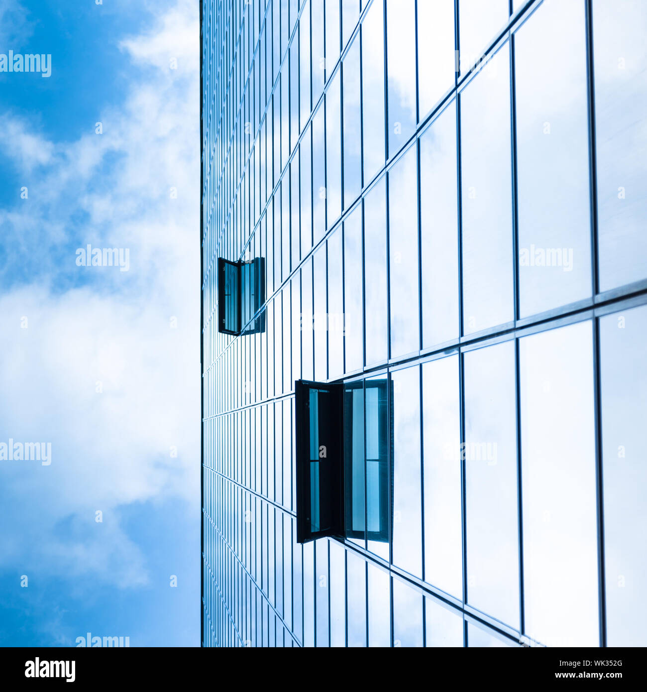 Modern facade of glass and steel with open window reflecting sky and ...