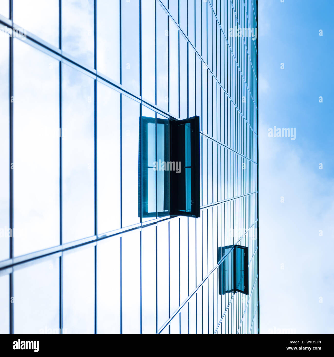 Modern facade of glass and steel with open window reflecting sky and ...