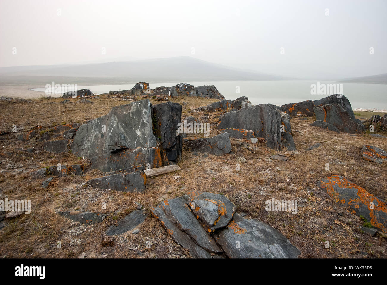 Beautiful black rocks sticking out of the ground with a lake and hills ...