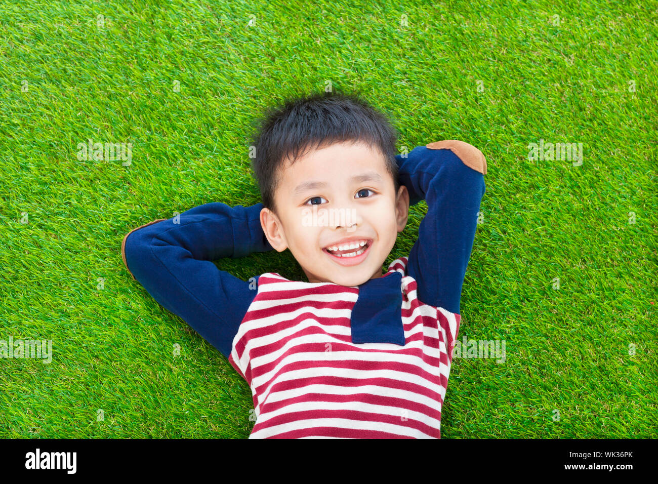 happy kid lying and holding his head on a meadow Stock Photo - Alamy