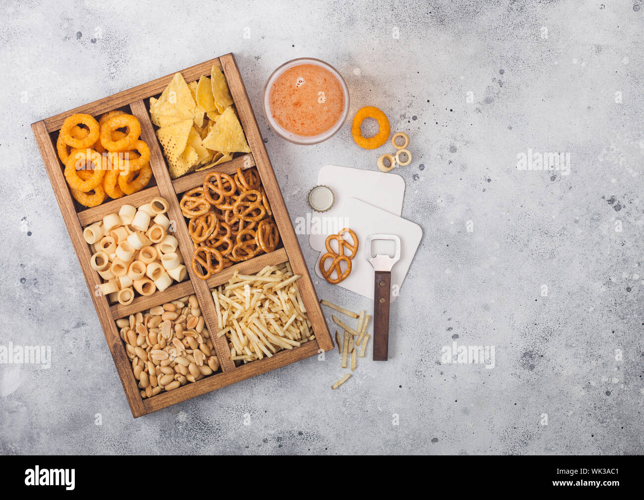 Glass of craft lager beer and opener with box of snacks on light ...