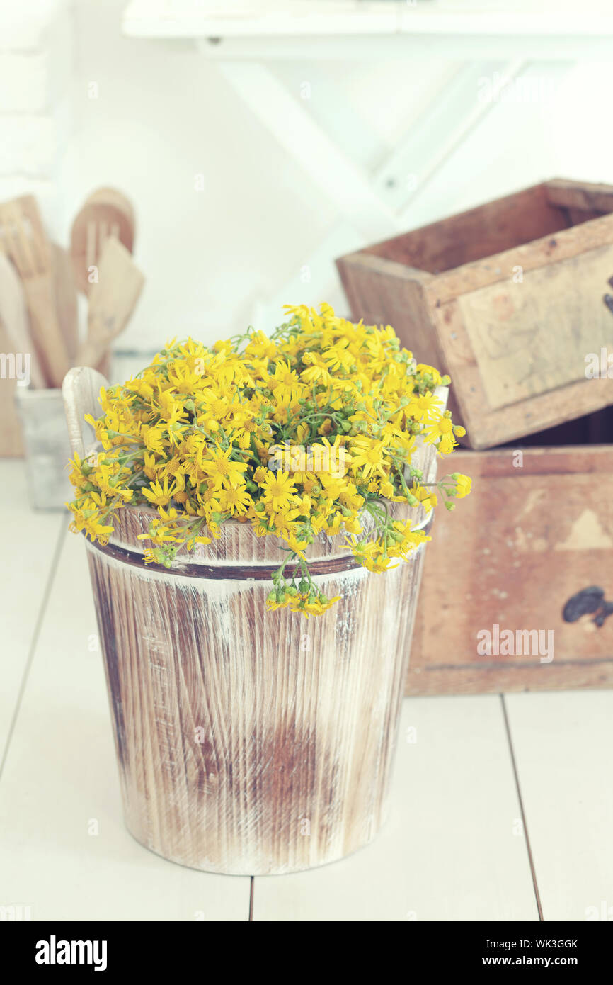 Rustic photo of bunch of simple flowers in a old bucket on white wooden ...