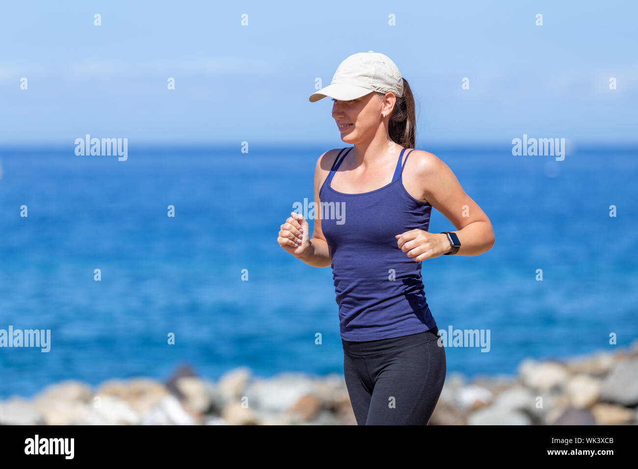 Young slim female runner near the sea jogging in the morning. Healthy ...