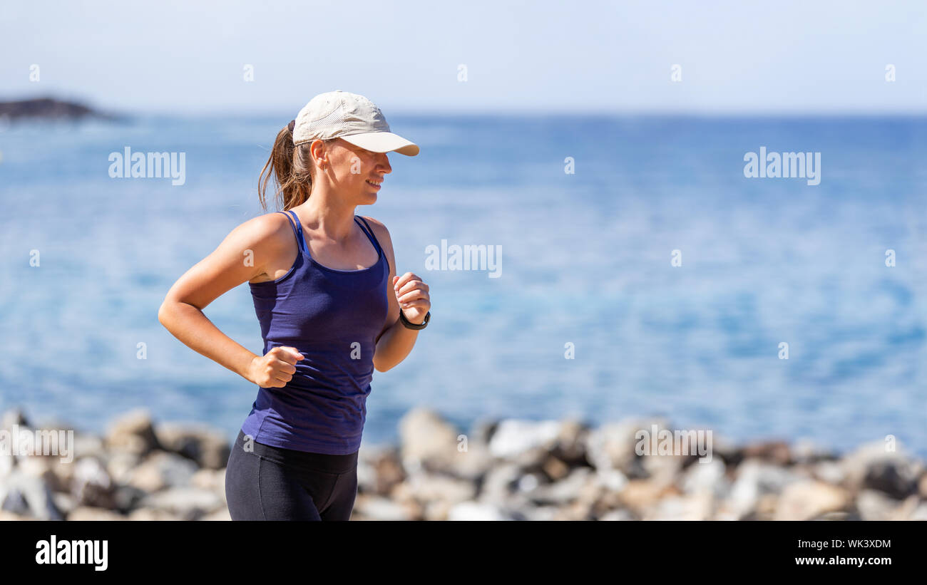 Young slim female runner near the sea jogging in the morning. Healthy ...