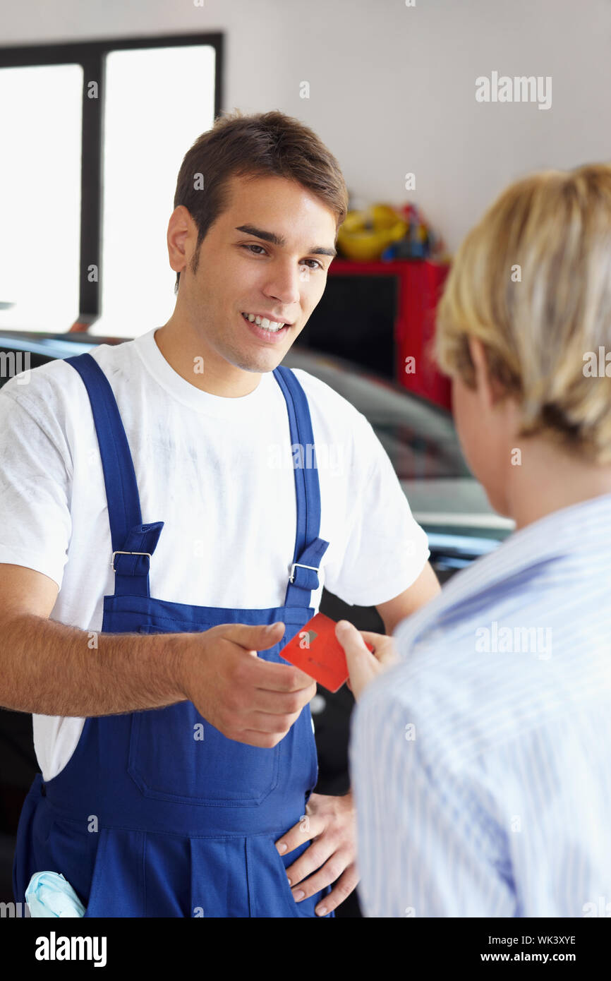 Rear view of woman giving credit card to mechanic Stock Photo - Alamy