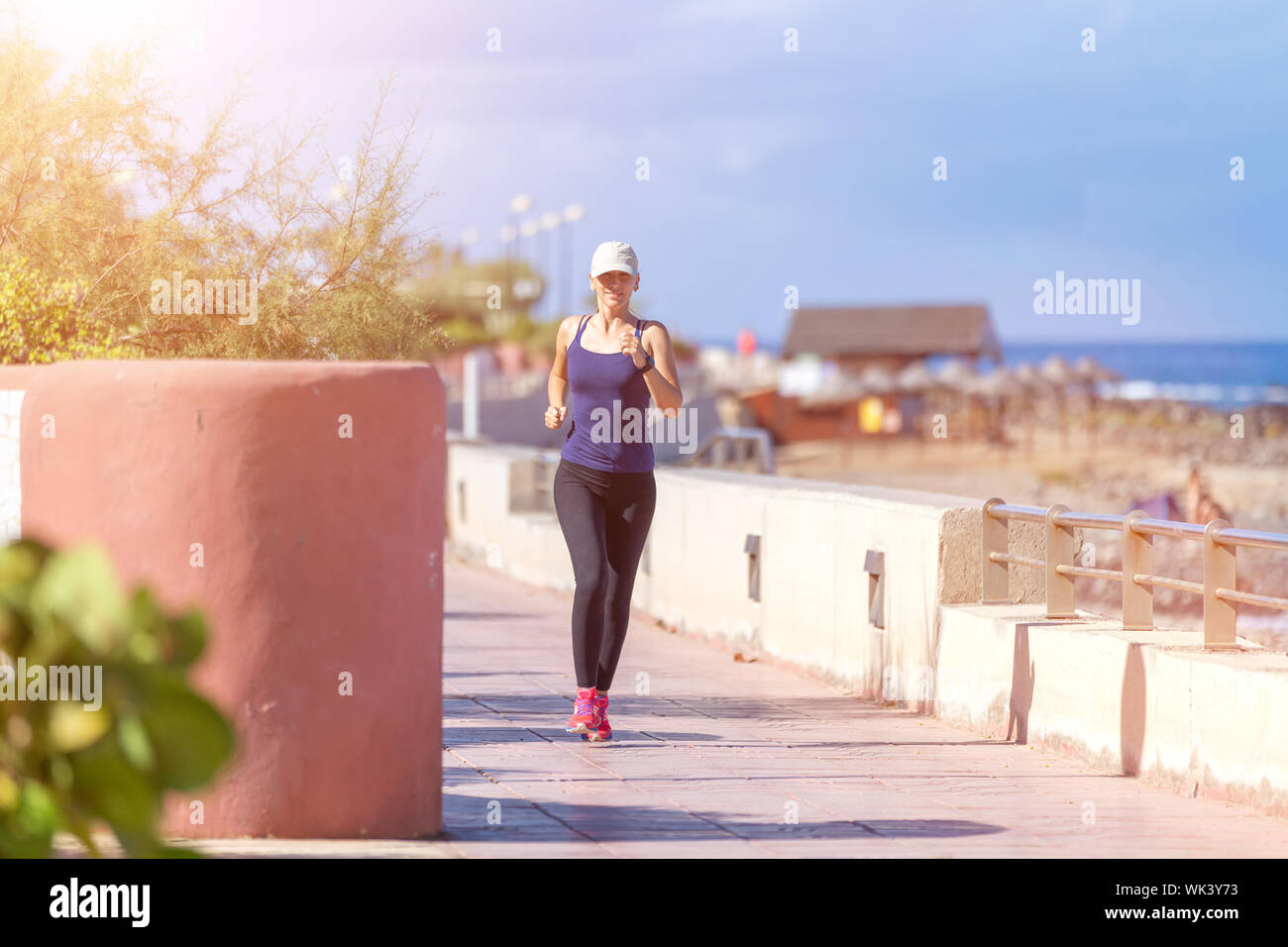 Young slim female runner near the sea jogging in the morning. Healthy ...