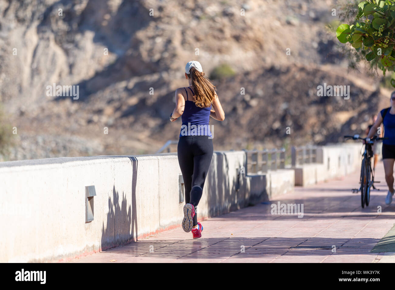 Young sporty woman jogging near the ocean. Back view of running girl ...