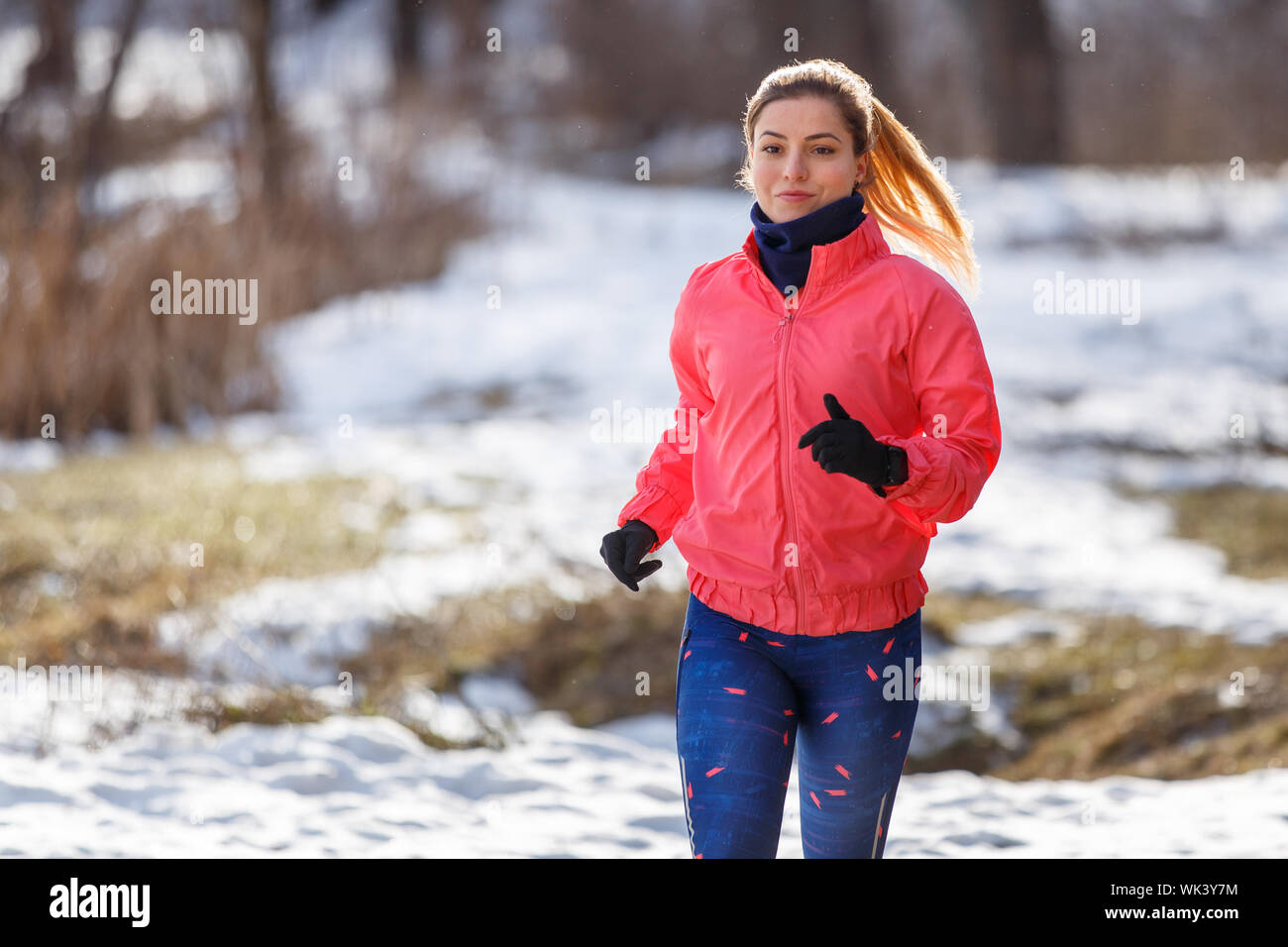 Young slim woman jogging in winter park. Smiling girl running in cold ...