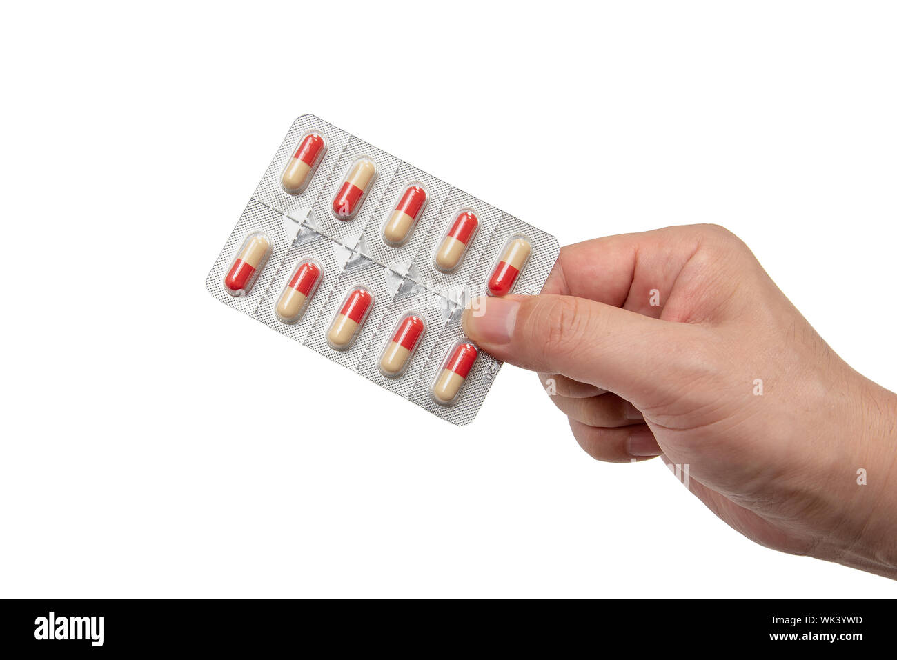 A man's hand holding a panel of red capsules on a white background ...