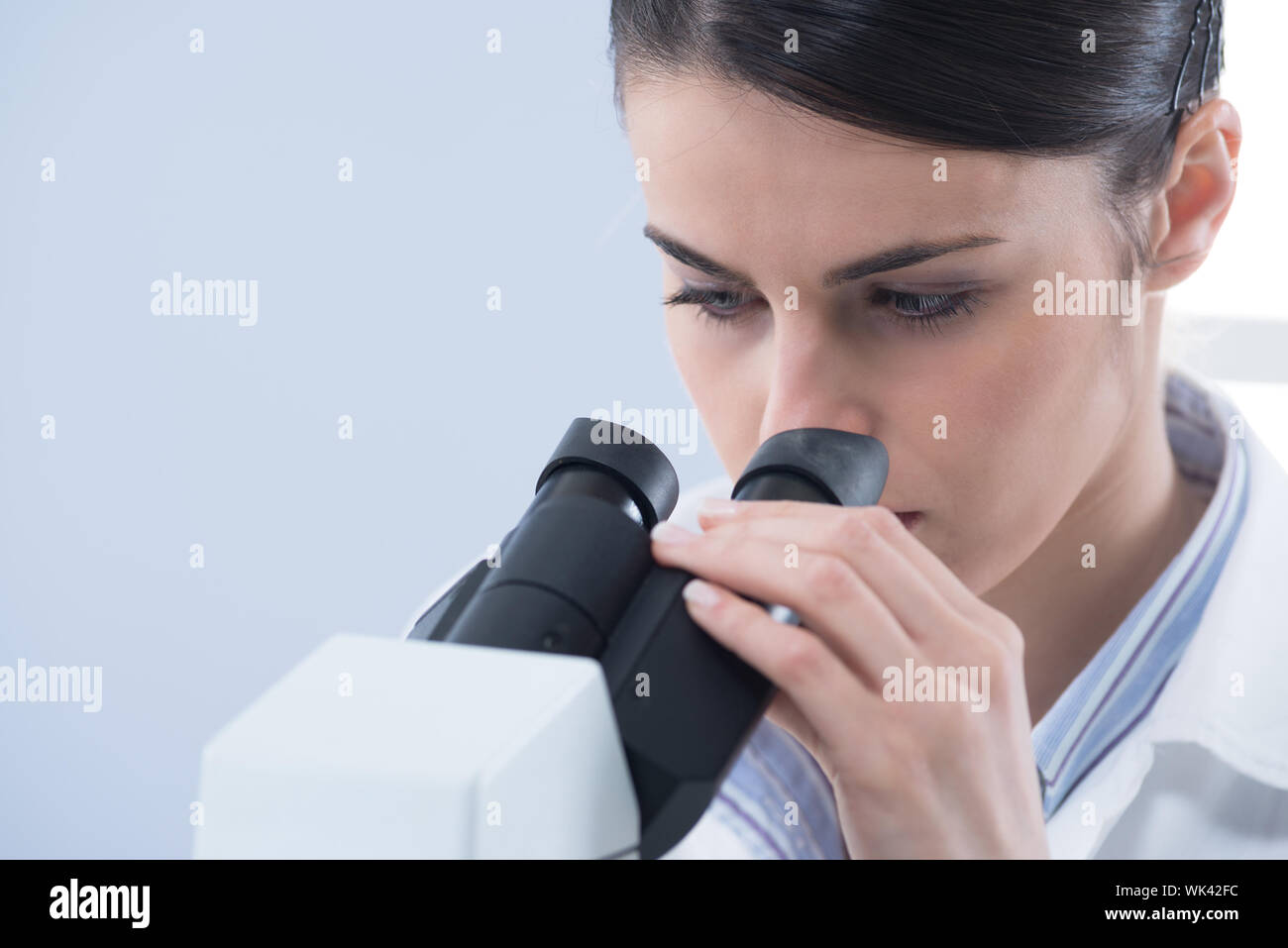 Young female researcher using microscope in the laboratory close up ...