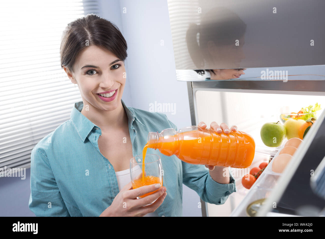 Cheerful young woman pouring fresh fruit juice into a glass Stock Photo - Alamy