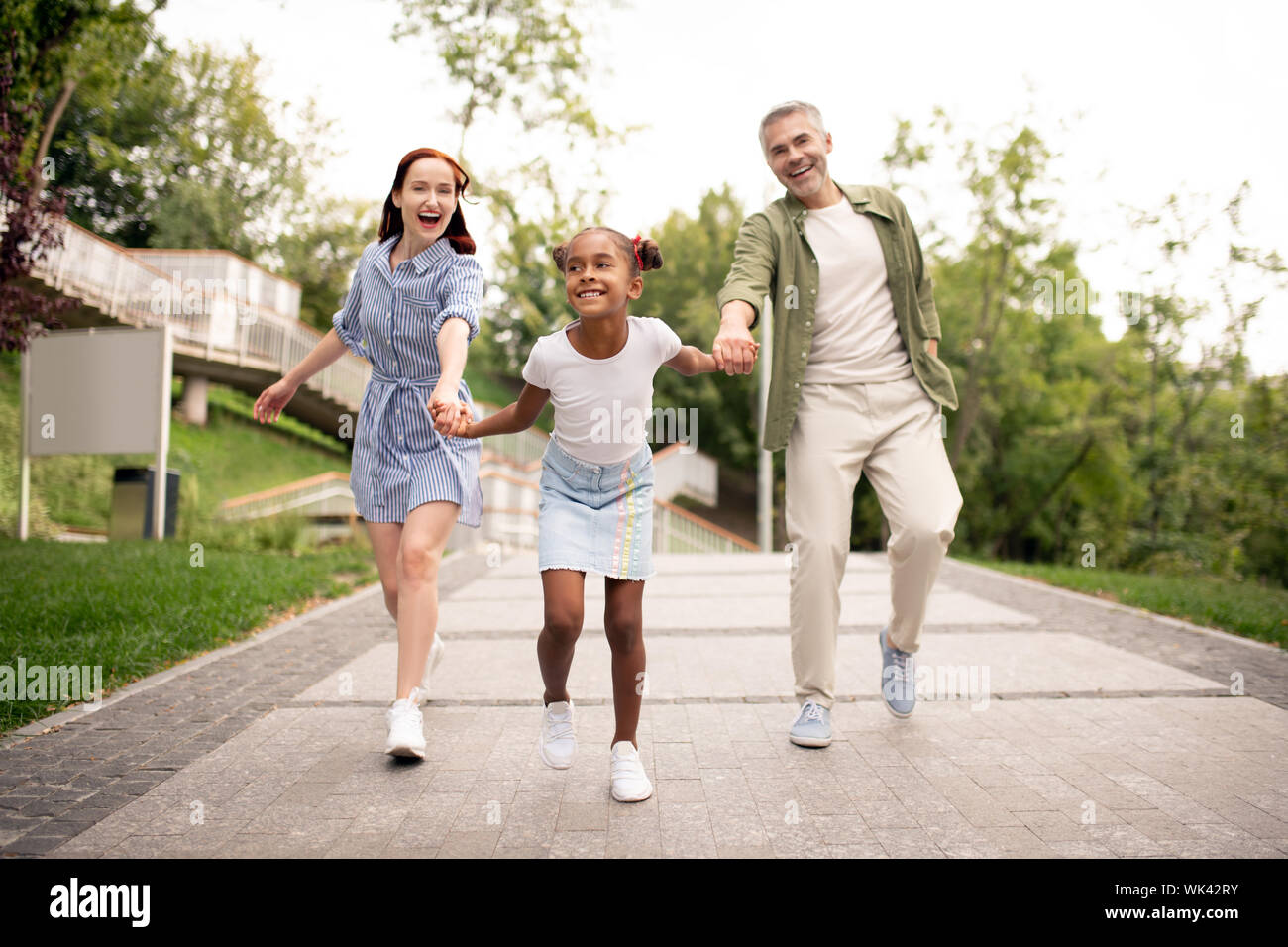 African-American daughter running while walking with parents Stock ...